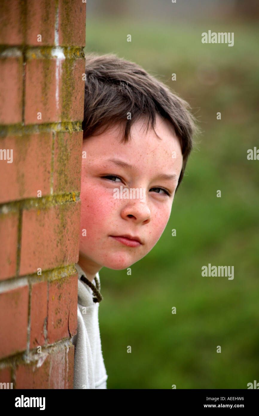 Vertical close up portrait of moody young boy looking serious at camera ...