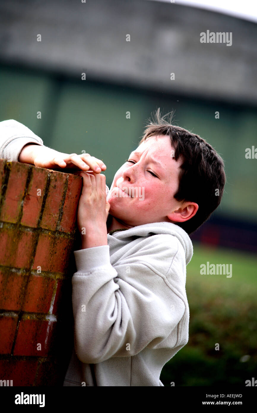 Vertical colour portrait of young boy climbing wall with effort showing ...