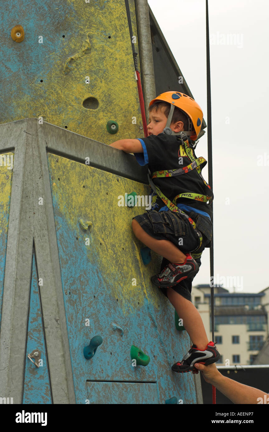 Young boy on climbing wall being helped with instructors hand on his ...