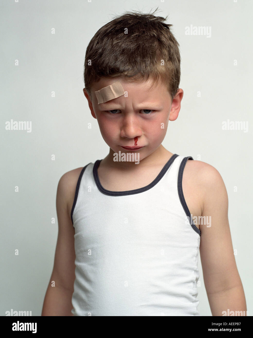 injured boy with plaster or band aid on his forehead and a nosebleed ...