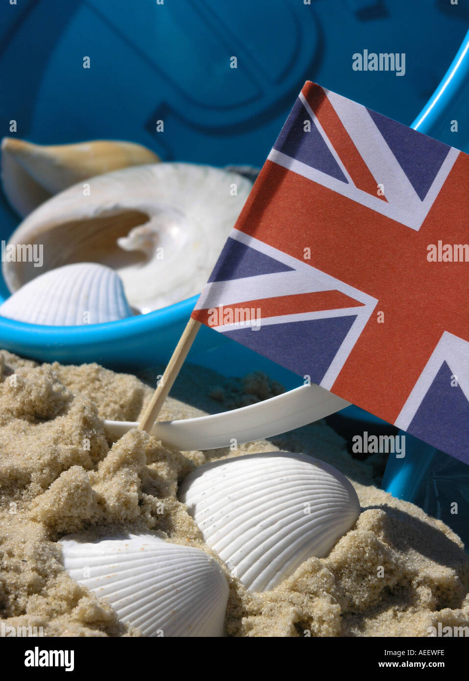 Union Jack paper flag on a beach with sea shells and a plastic spade ...