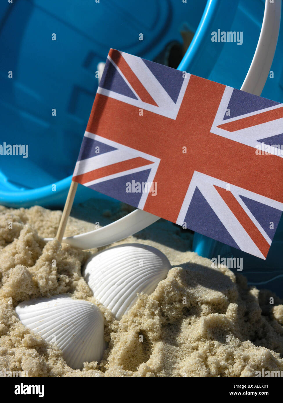 Plastic childs bucket paper union jack flag and shells on a sandy beach ...