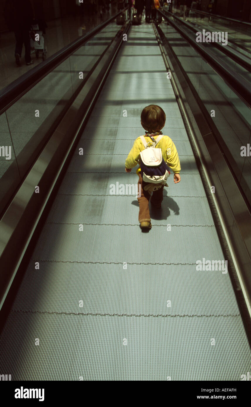 A male child striding out alone on a moving-walkway at an Narita ...