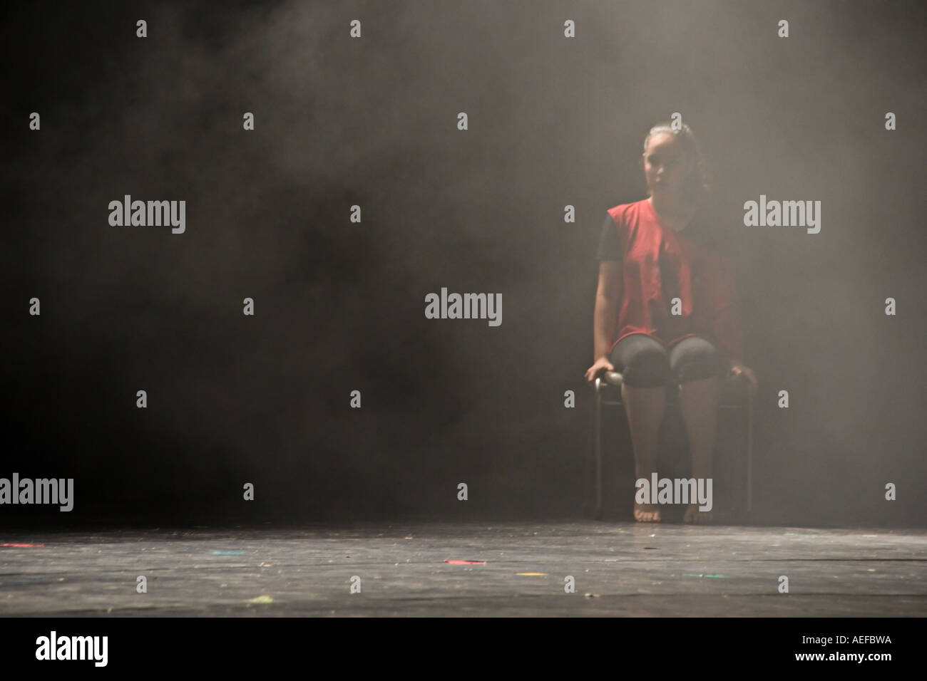 Stock photo of a dancer on stage sitting on a chair in a mist of ...