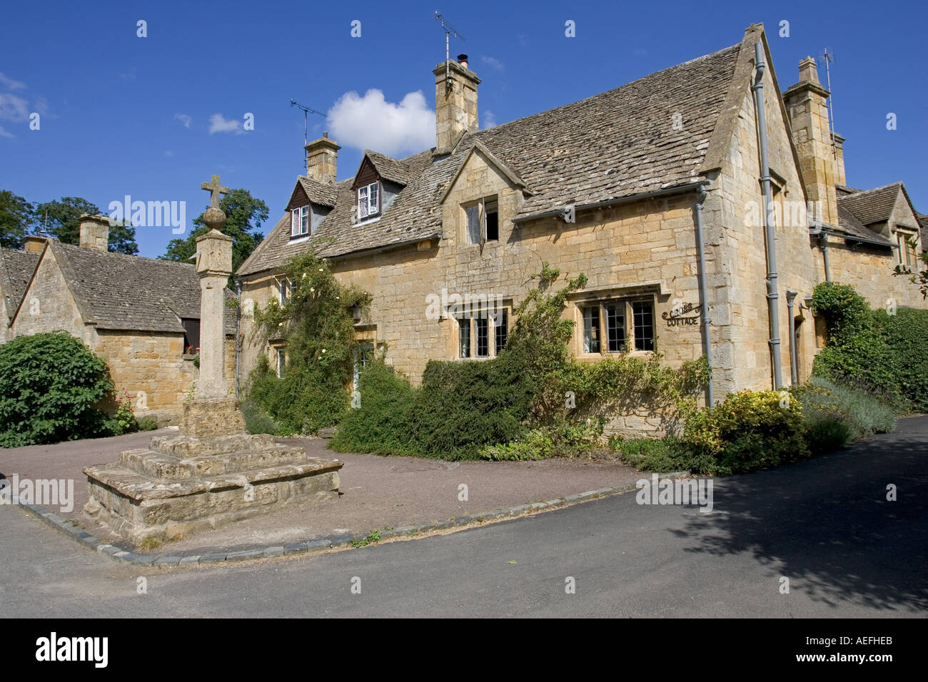 Cross Cottage with medieval cross outside village of Stanton Cotswolds ...