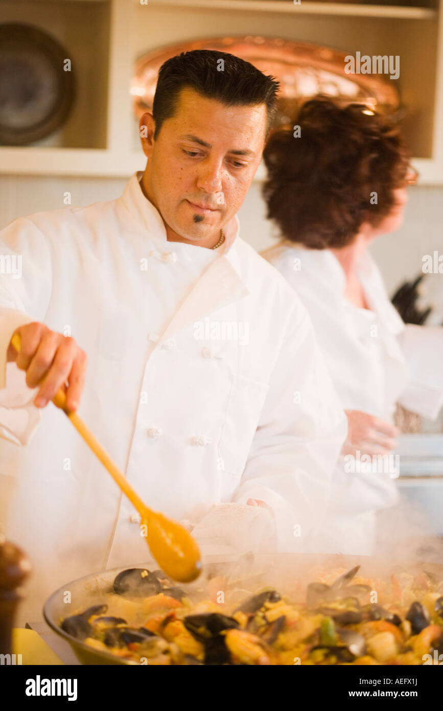 a chef prepares a traditional Spanish dish of paella at a cooking class ...