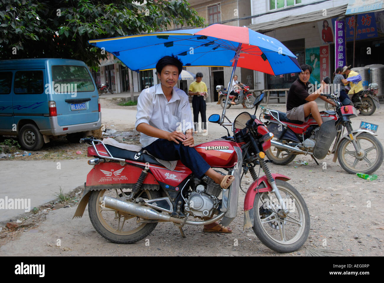 A Chinese Motorcycle Taxi Driver with an Umbrella Stock Photo - Alamy