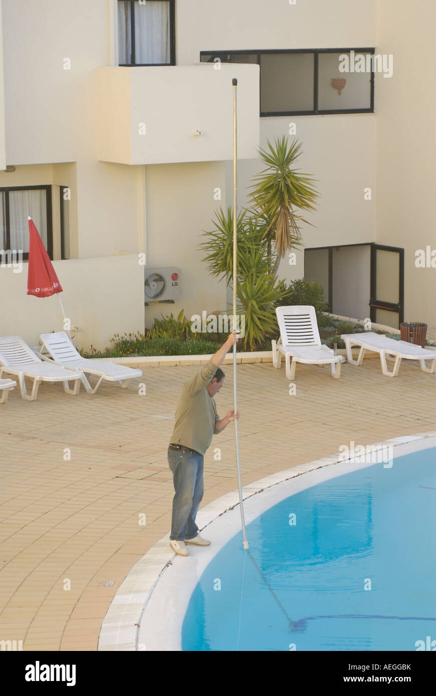 Man cleaning a hotel swimming pool in albufera portugal Stock Photo - Alamy