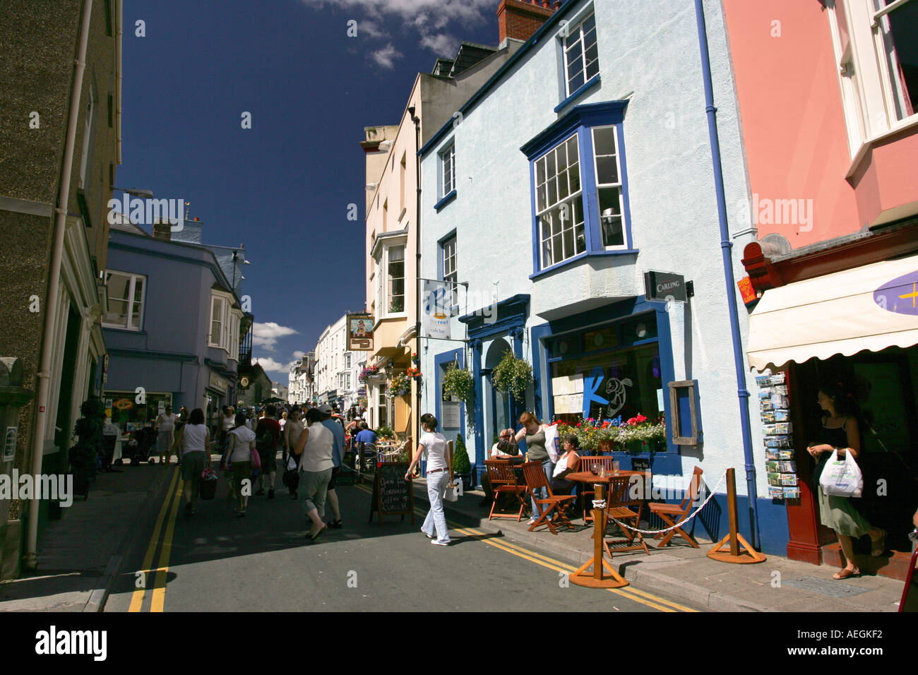 Tourists eat and drink at a pavement cafe in colourful Tenby town ...