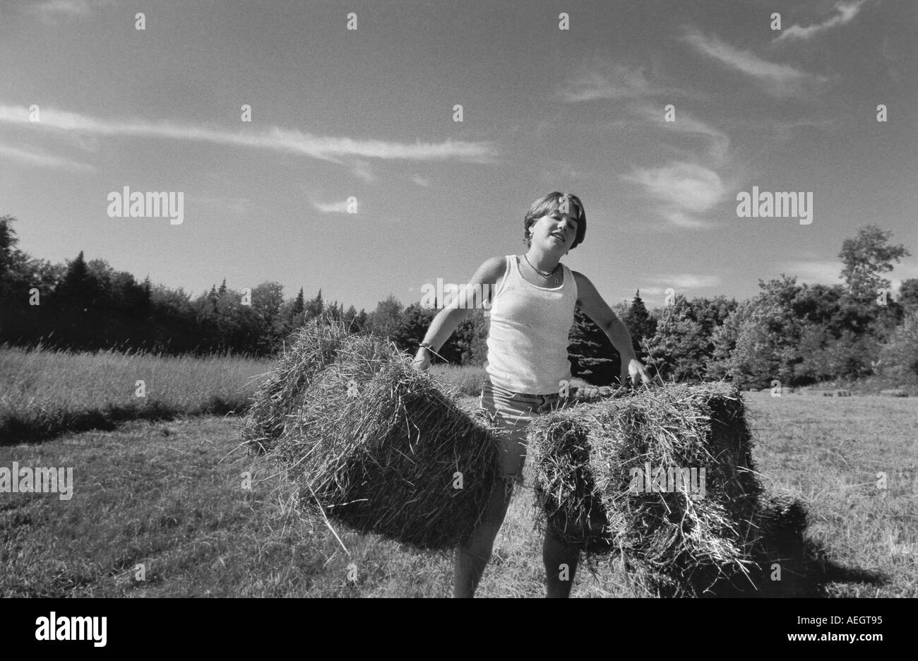 Farm girl carrying bales of hay Stock Photo - Alamy