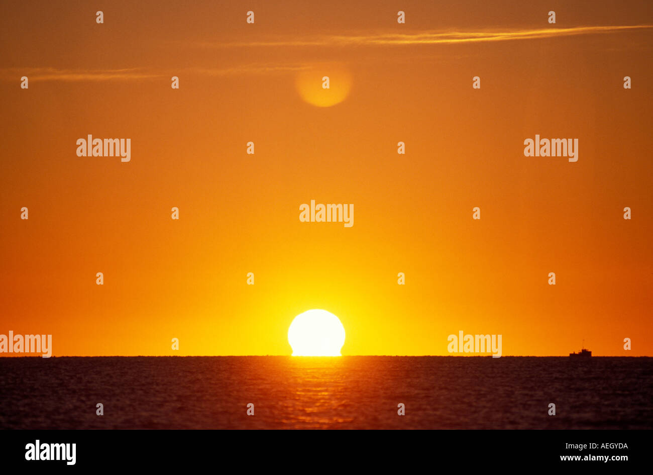 sun just peaking over the horizon at sunrise with fishing boat in the ...