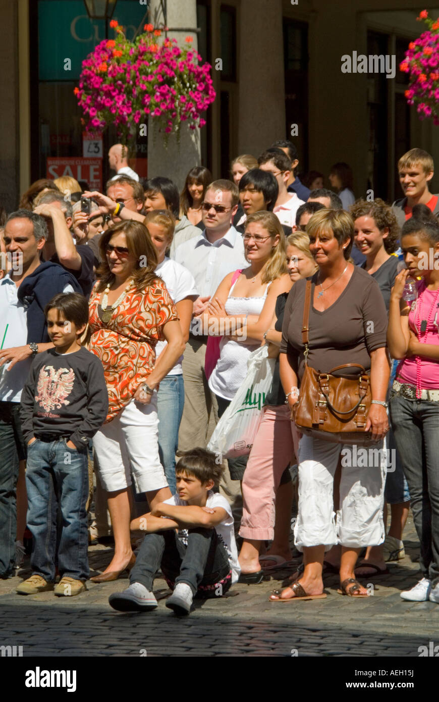 Vertical close up of crowds of people watching a street performer in ...