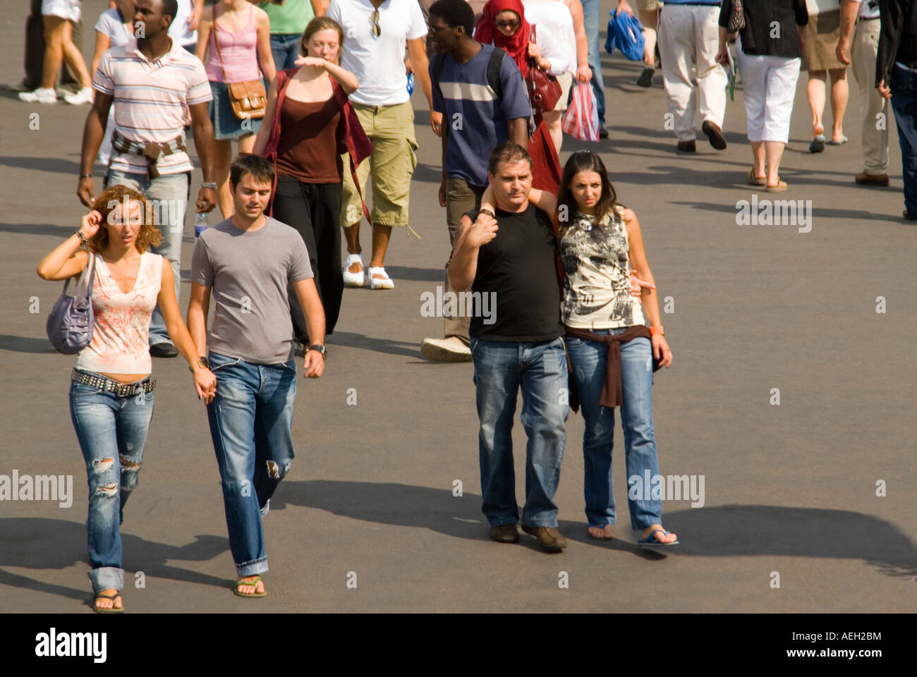 Horizontal aerial close up of crowds of people walking along in the ...