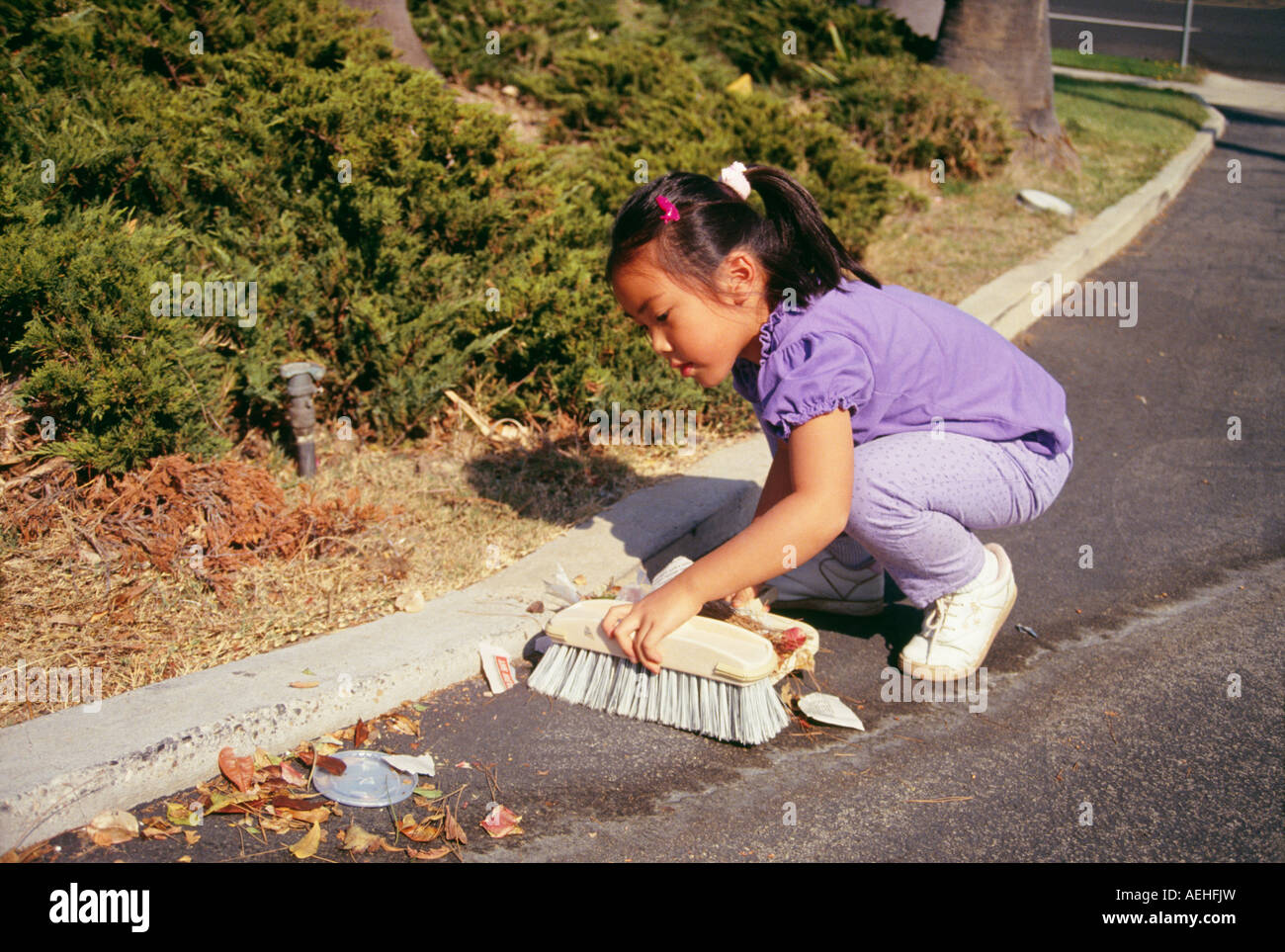 Girl 5-7 year old sweeping driveway brushing trash leaves clutter chore ...
