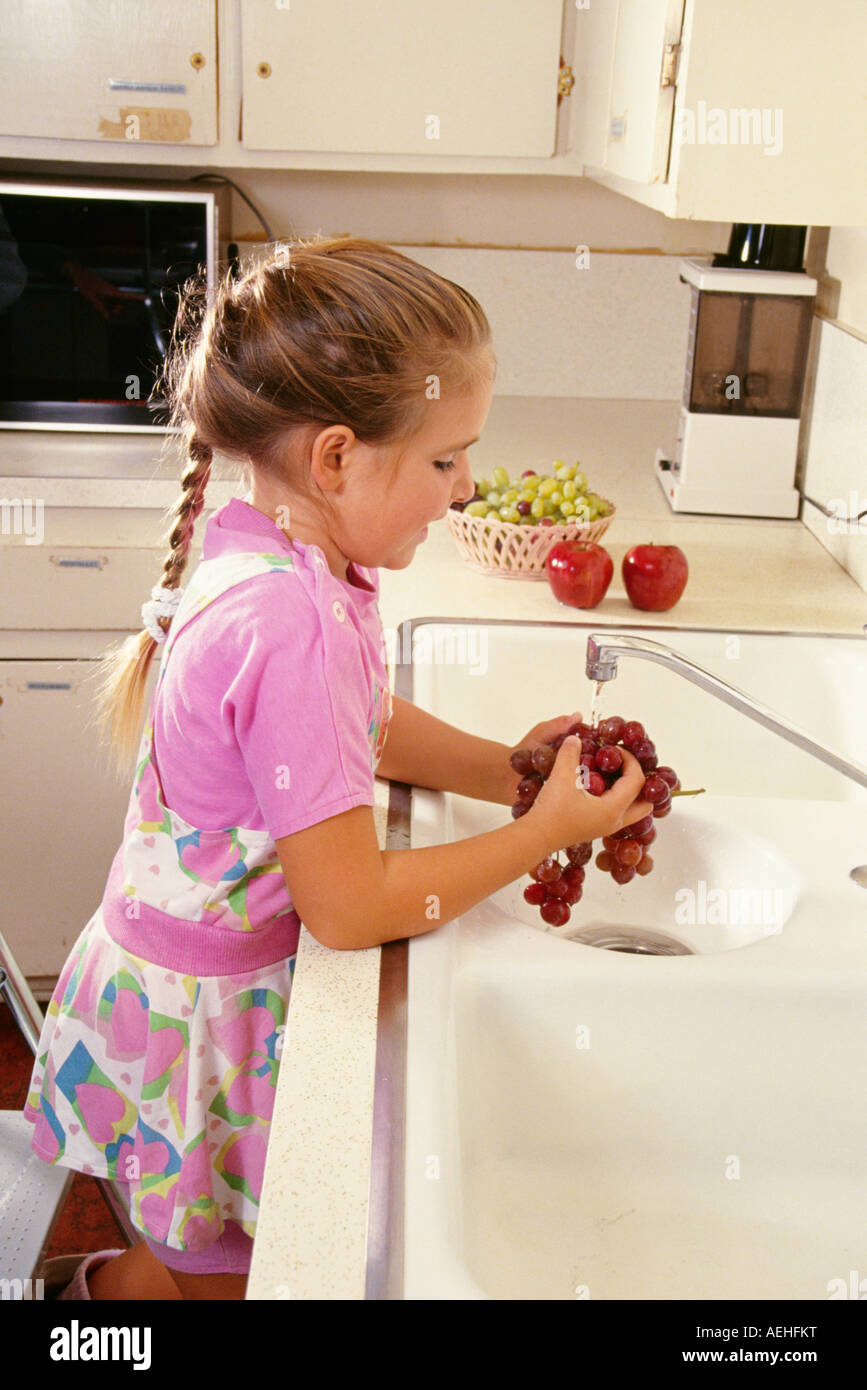 Girl 5-6 year old washing grapes food child children helping in kitchen ...