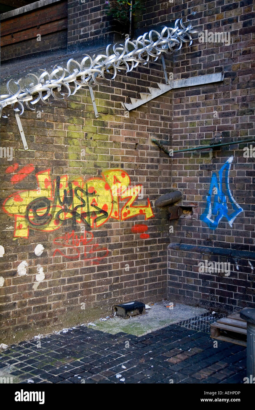 Urban scene, alley way with security wire and graffiti Stock Photo - Alamy