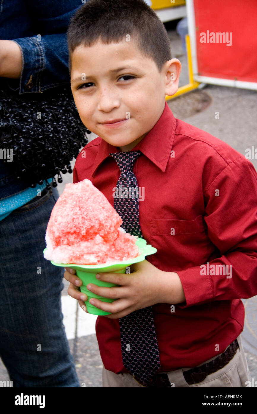 Young Chicano boy enjoying giant snow cone decked out in nice shirt and ...