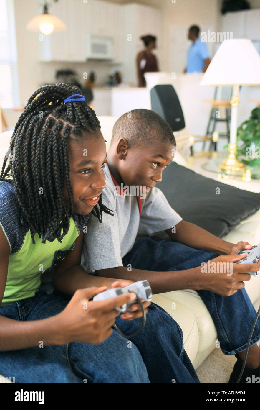 Brother and sister playing video games parents in background Stock ...