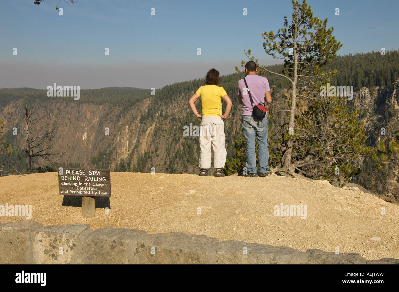 People ignoring a "danger" sign at a cliff at Yellowstone National Park ...