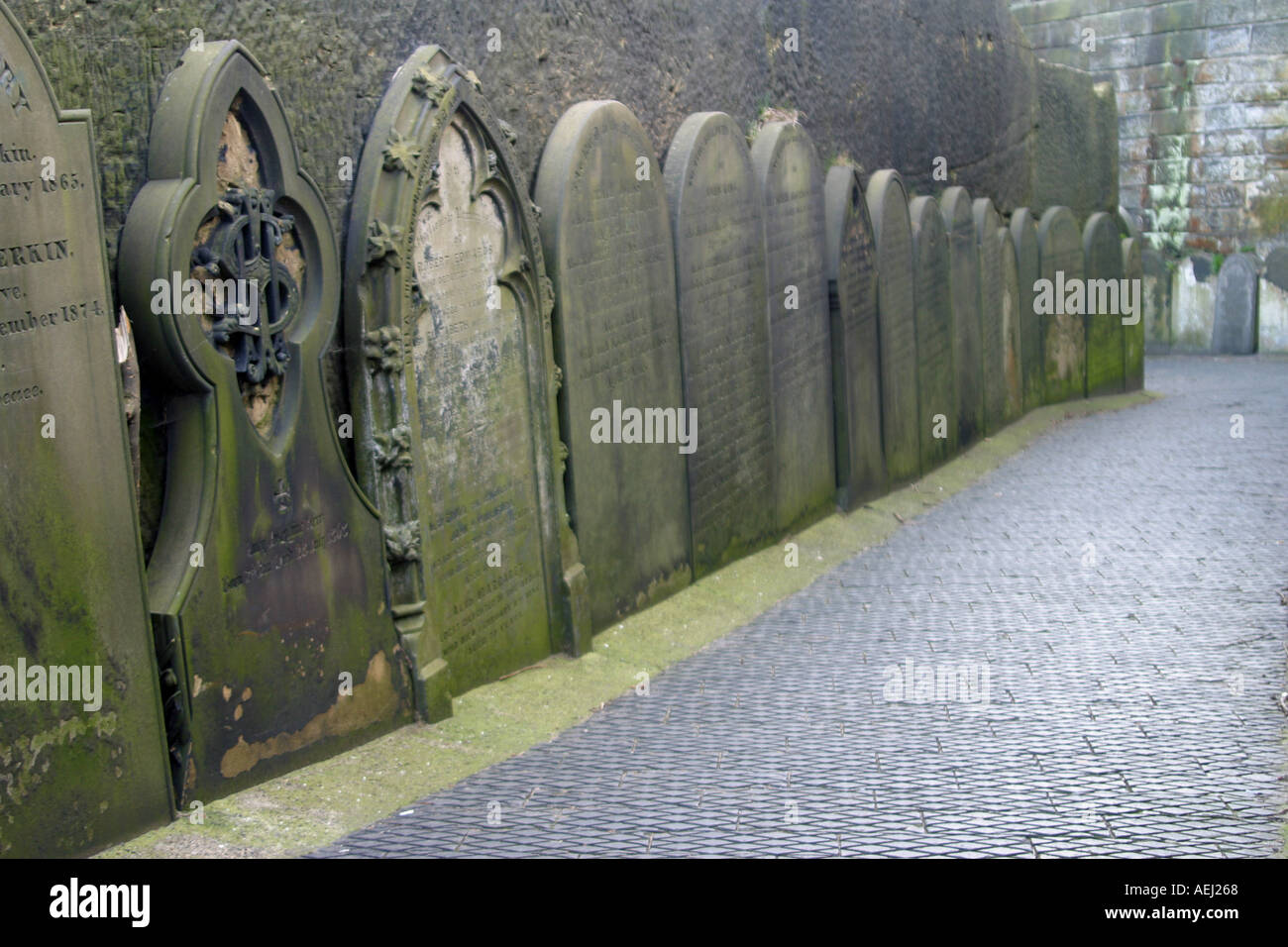 A row of gravestones lined up along the cobblestone road leading down ...