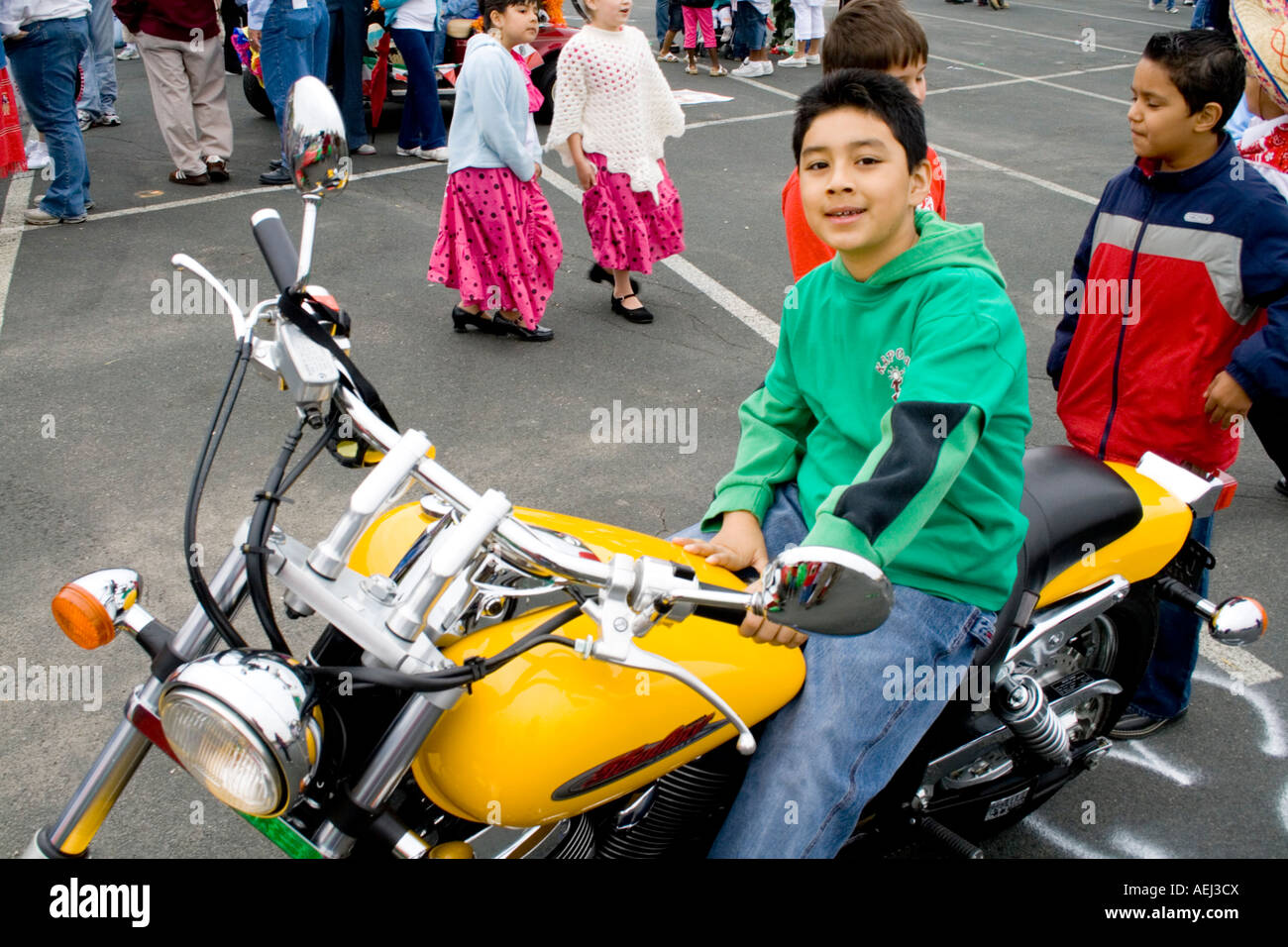 Chicano boy age 10 getting the feel of yellow motorcycle. Cinco de Mayo ...