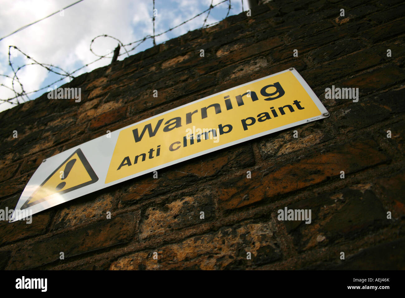 Looking up at warning sign on wall with barbed wire above Stock Photo ...