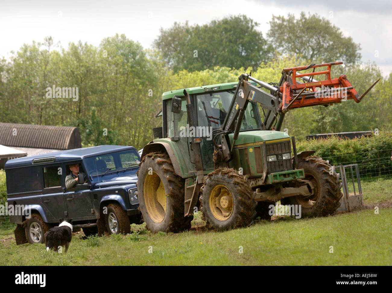 A SHEEP FARMER DRIVING A LAND ROVER DEFENDER BEHIND A TRACTOR ON A ...