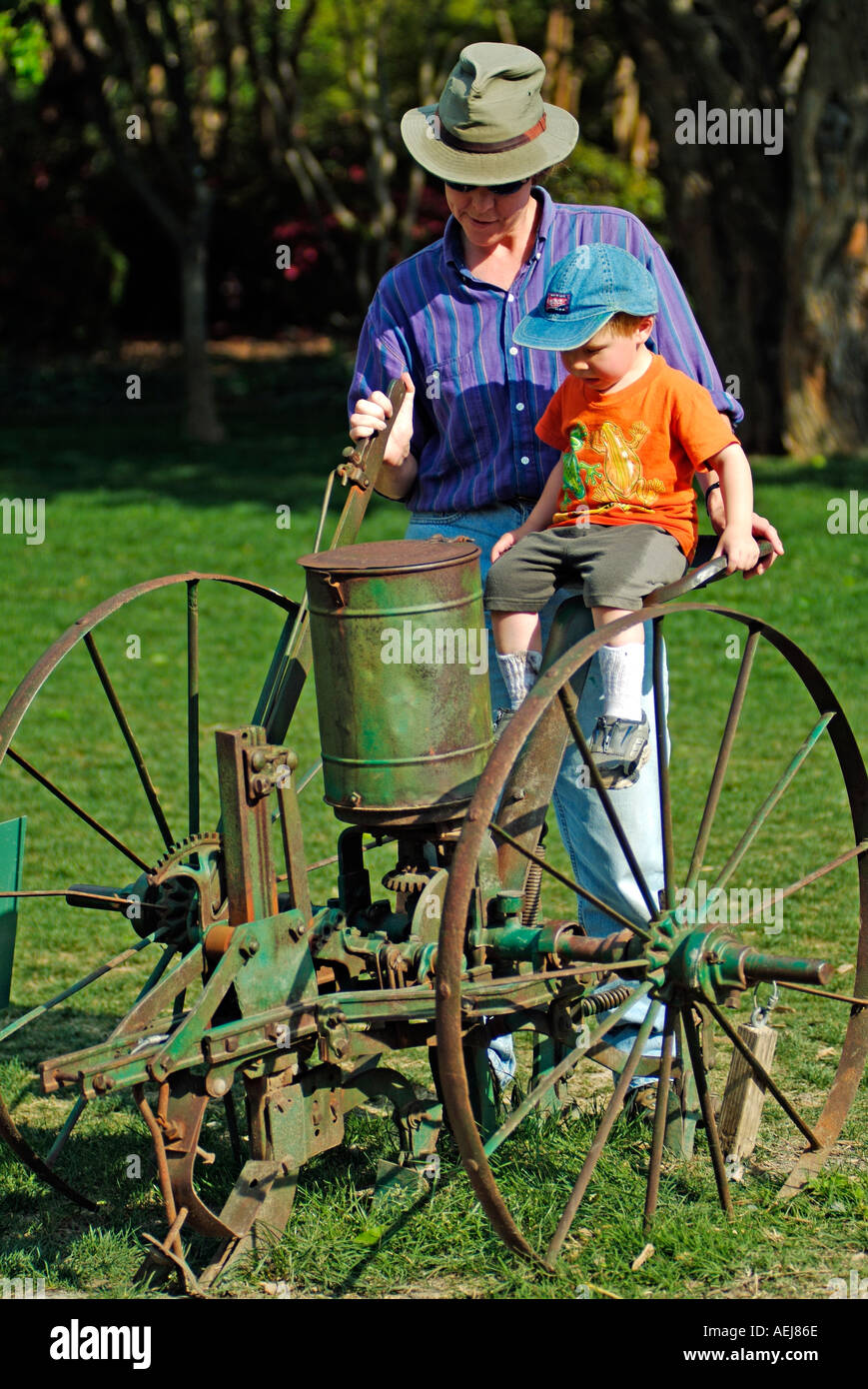 Young boy sitting on an old metal plow Stock Photo - Alamy