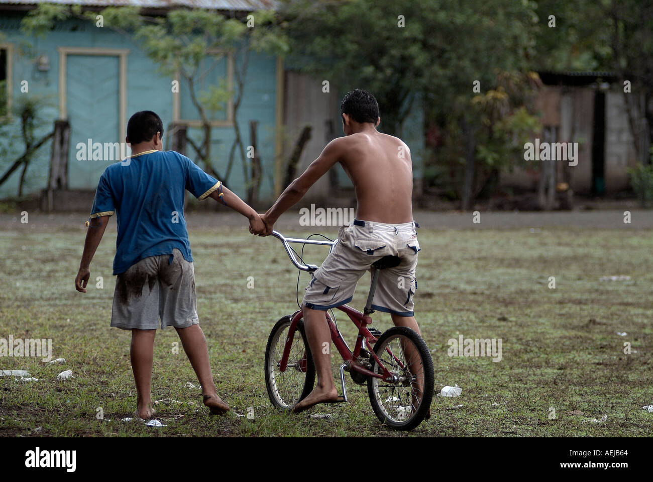 Two young boys playing with a bike in a soccer field Stock Photo - Alamy