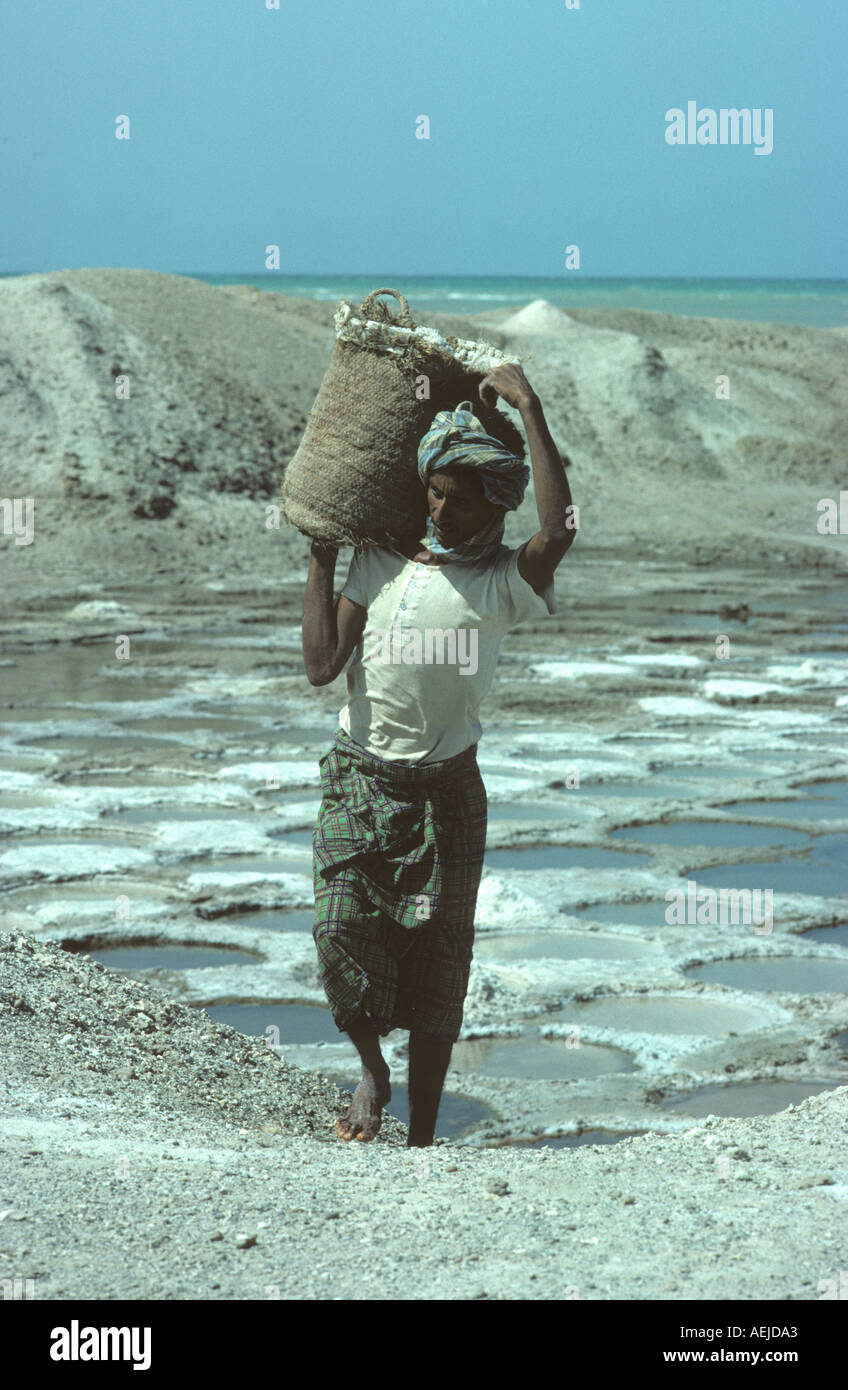 Man carrying salt evaporated from pans of seawater at Yachtil near ...