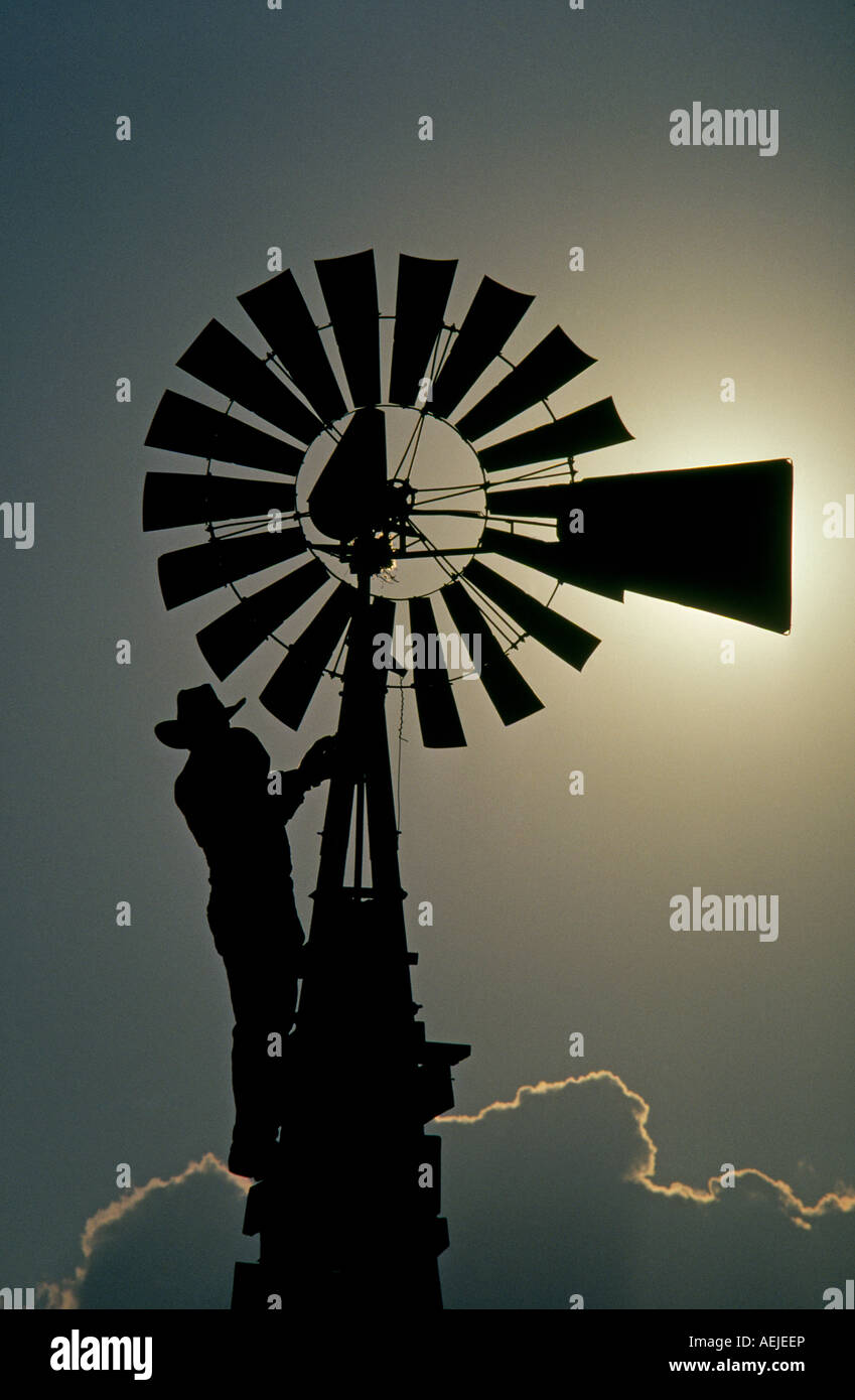 A cowboy works on the mechanical innards of his water pumping wooden ...