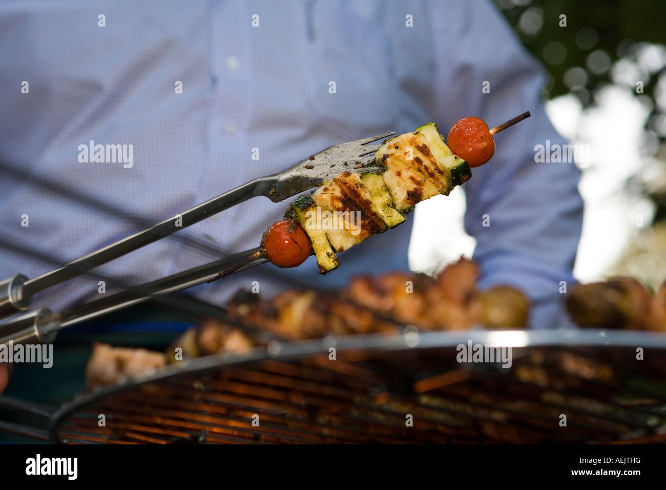 A vegetable spit on a grill, getting turned-over by the cook Stock ...