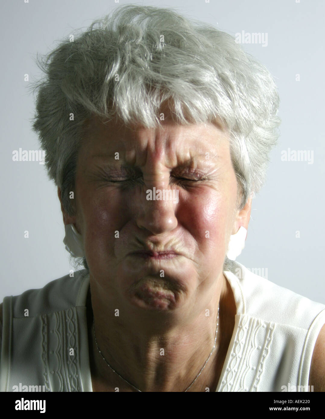 Woman aged sixty pulling a face under stress or holding her breath ...