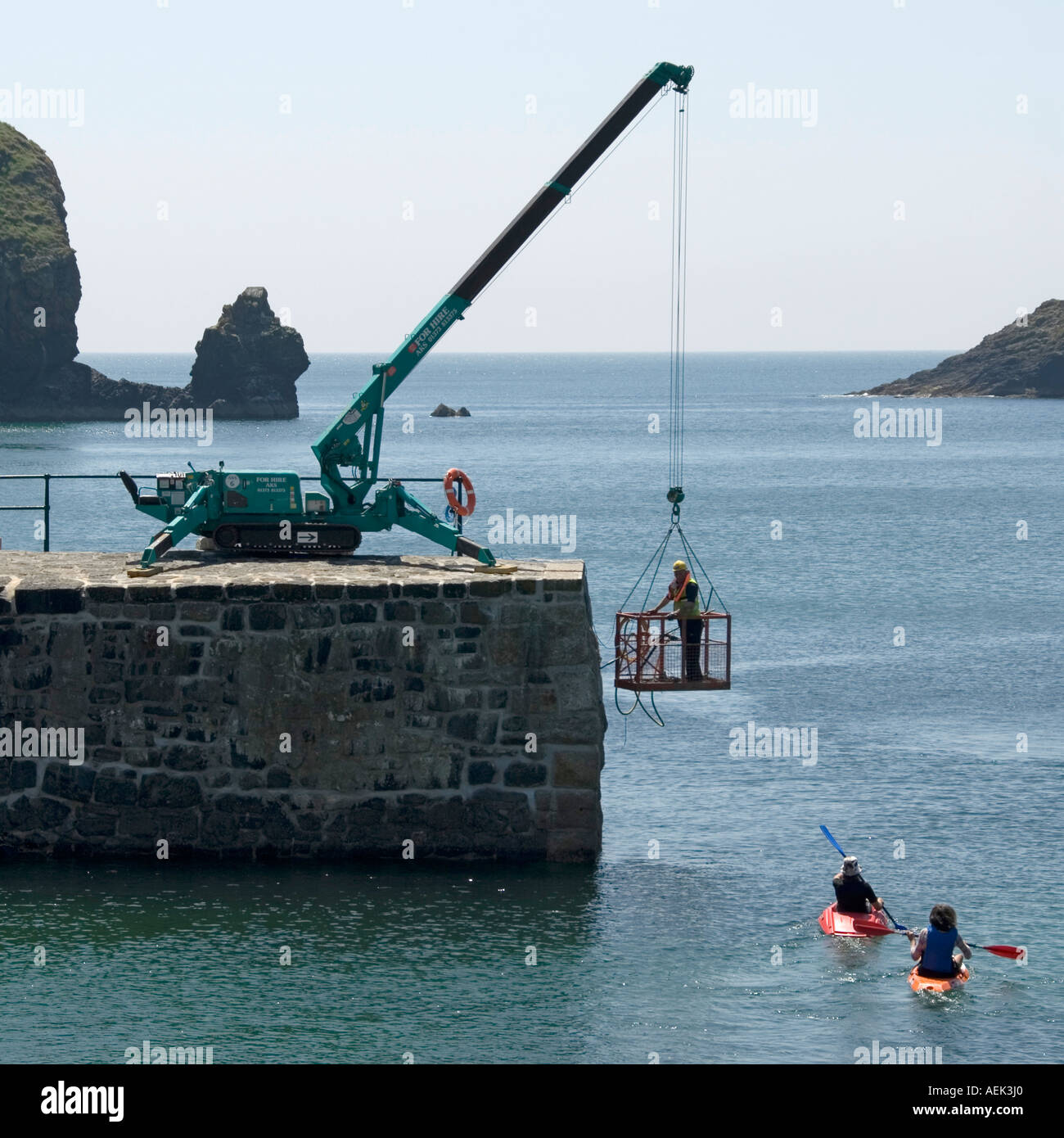 Mullion two canoeists leave harbour wall entrance with workman using ...