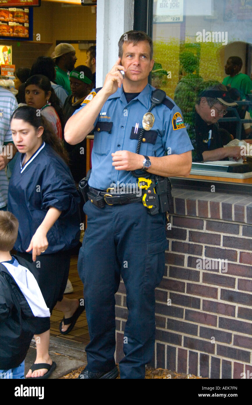 Policeman checking in with his cell phone in front of fast food ...