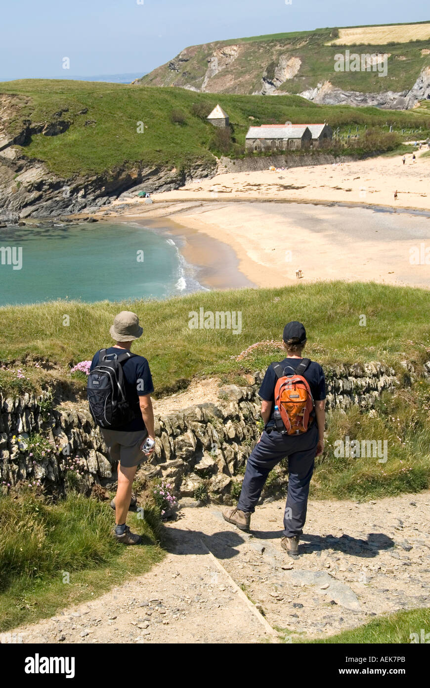 Walkers stop on South West Coast Path admire seaside beach at Church ...