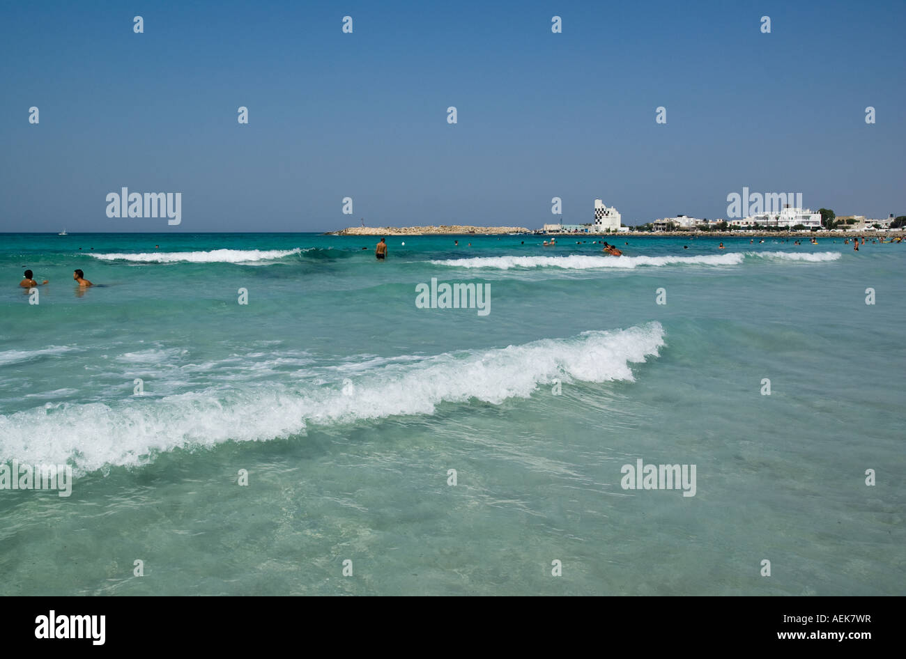 Transparent blue sea with little port on the background Stock Photo - Alamy