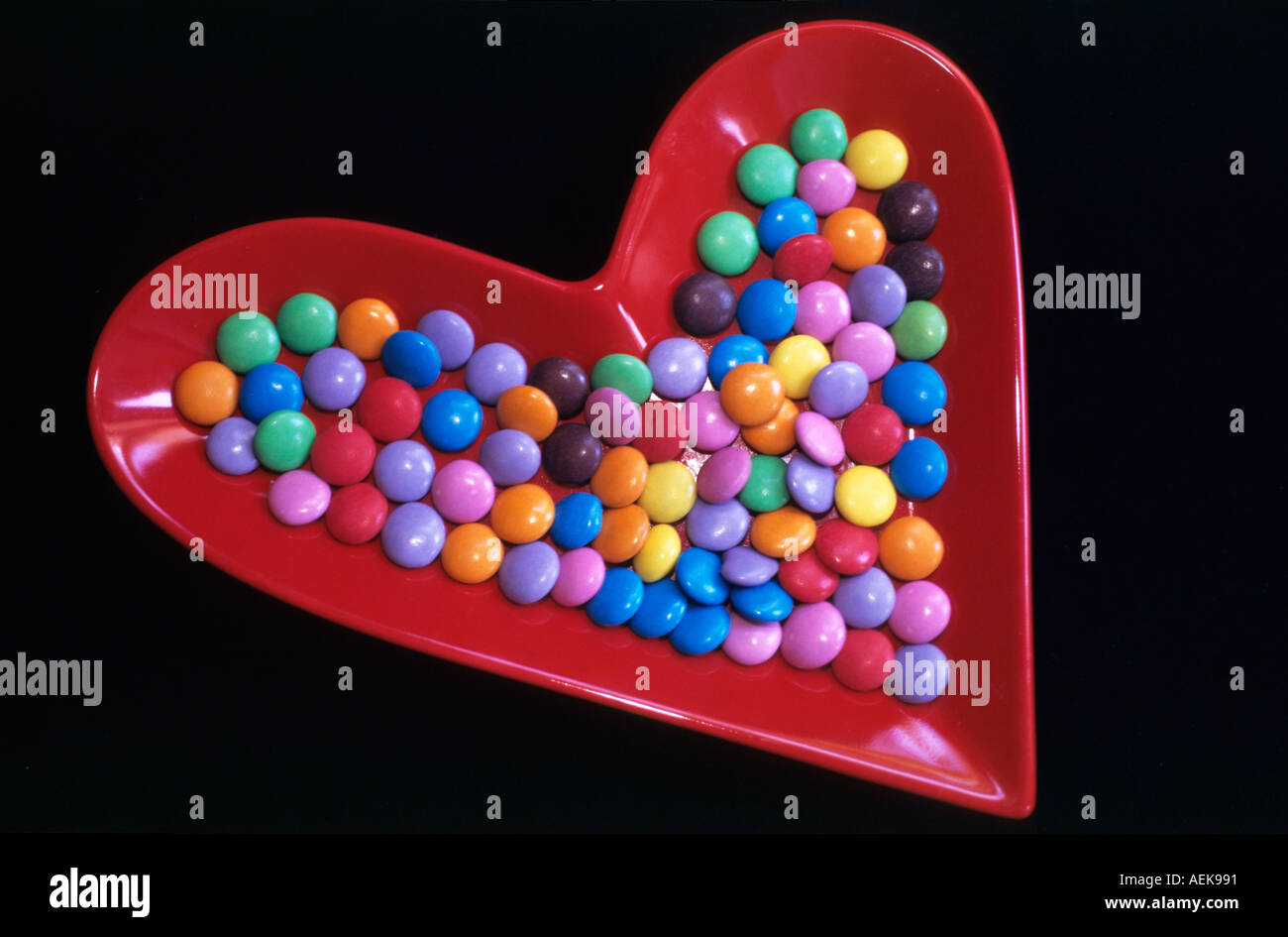 Red heart shaped dish full of Smarties Stock Photo - Alamy