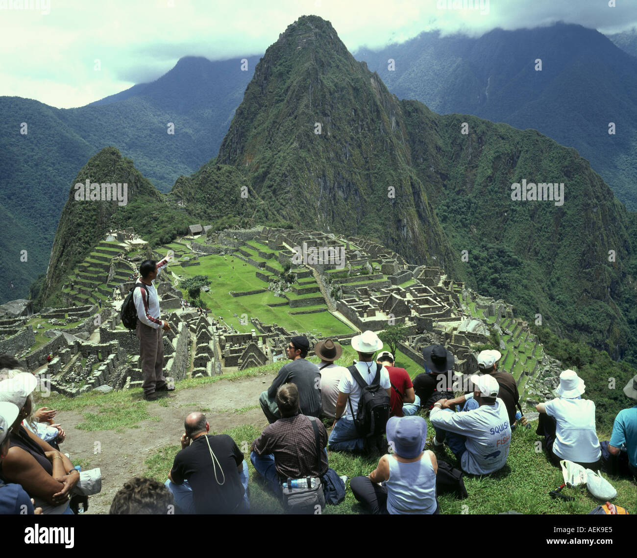 Tourists at Machu Picchu listen to a guide as they look across the ...