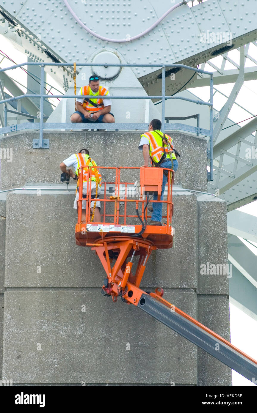 Bridge workers perform maintenance wearing safety gear and reflective ...
