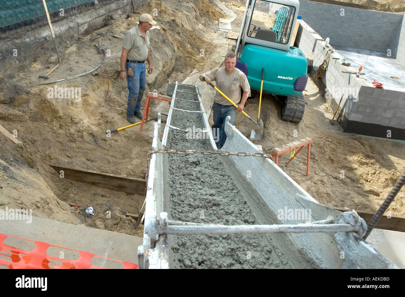 Foundation workers pull wet cement from truck to form footing for the ...