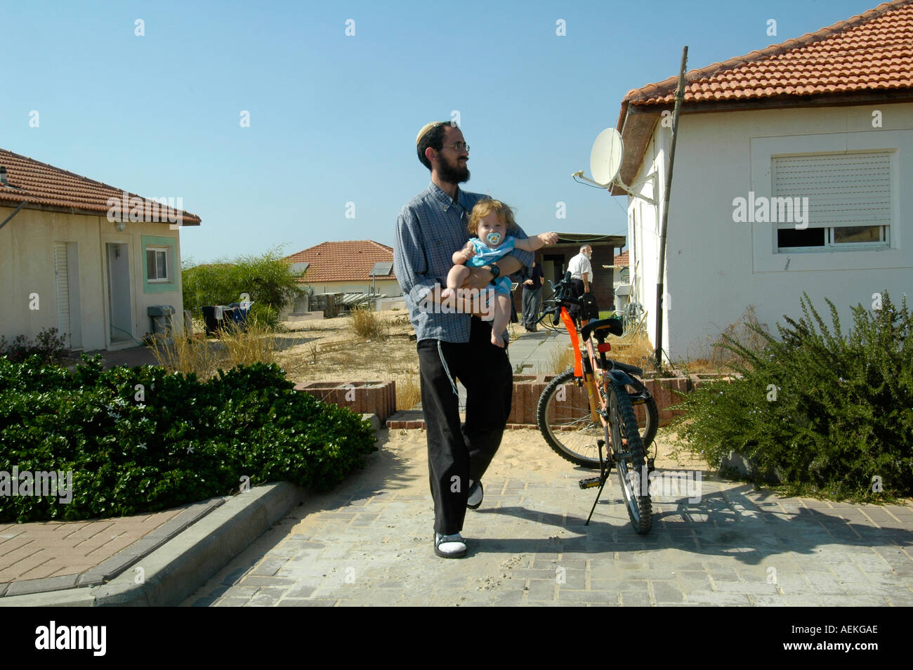 A religious Jewish settler carrying his son in Neveh Dekalim Jewish ...