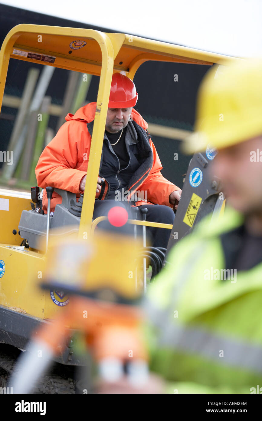 CONSTRUCTION SITE WORKERS WITH SITE LEVEL AND DIGGER DRIVER Stock Photo ...