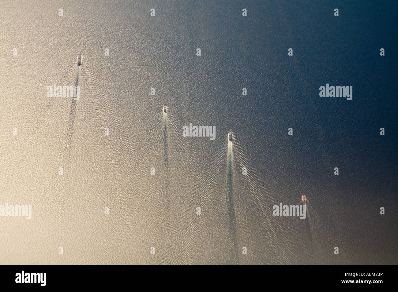 Four ships moving through the water in the same direction in the ...