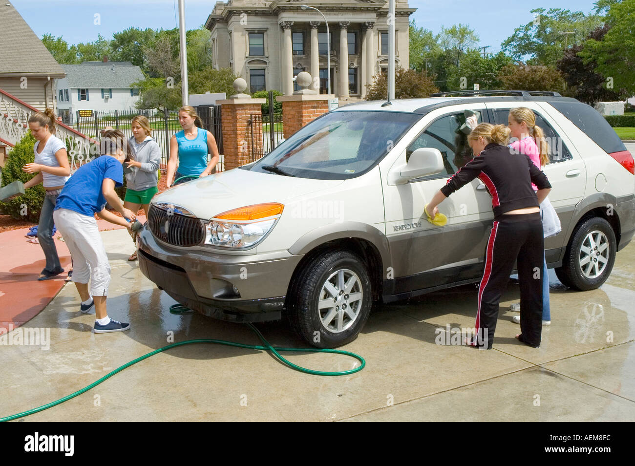 Group of teen volunteers hold a car wash to raise money for a project ...