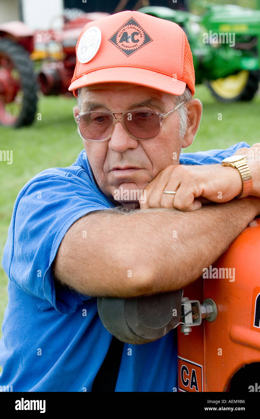 Portrait of a farmer leaning on a small tractor Stock Photo - Alamy