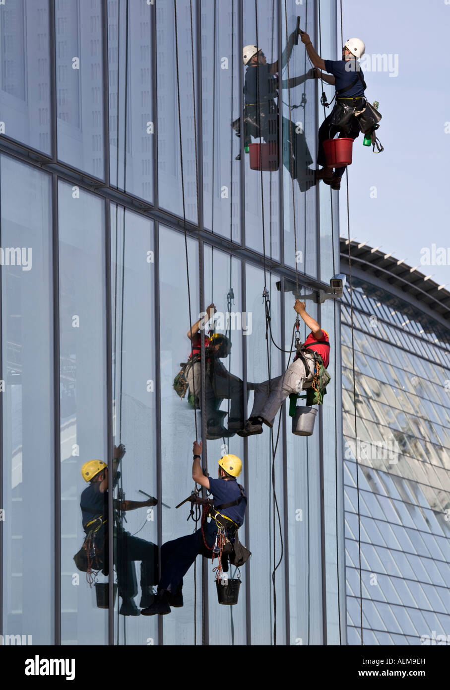 Window cleaners abseiling down a modern office block, Glasgow, Scotland ...