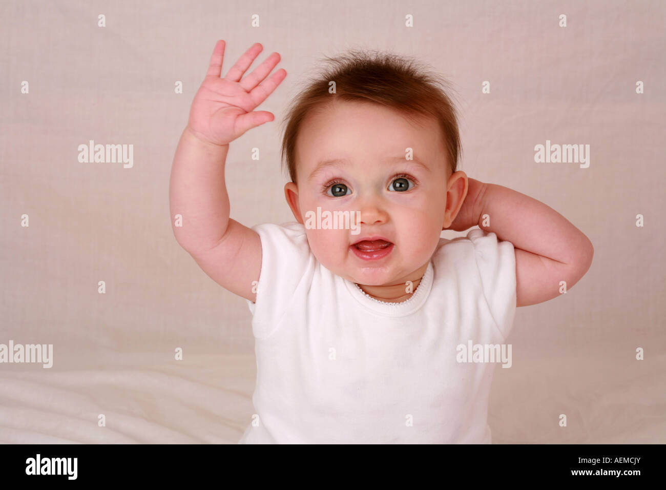 Gorgeous cute angelic newborn baby holds one hand behind head and waves ...