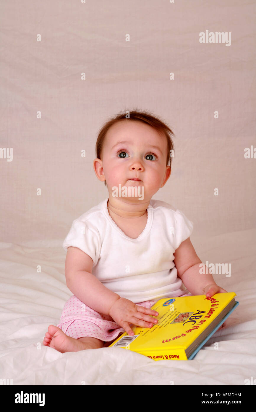 Angelic cute newborn baby infant in first year sitting upright holding ...