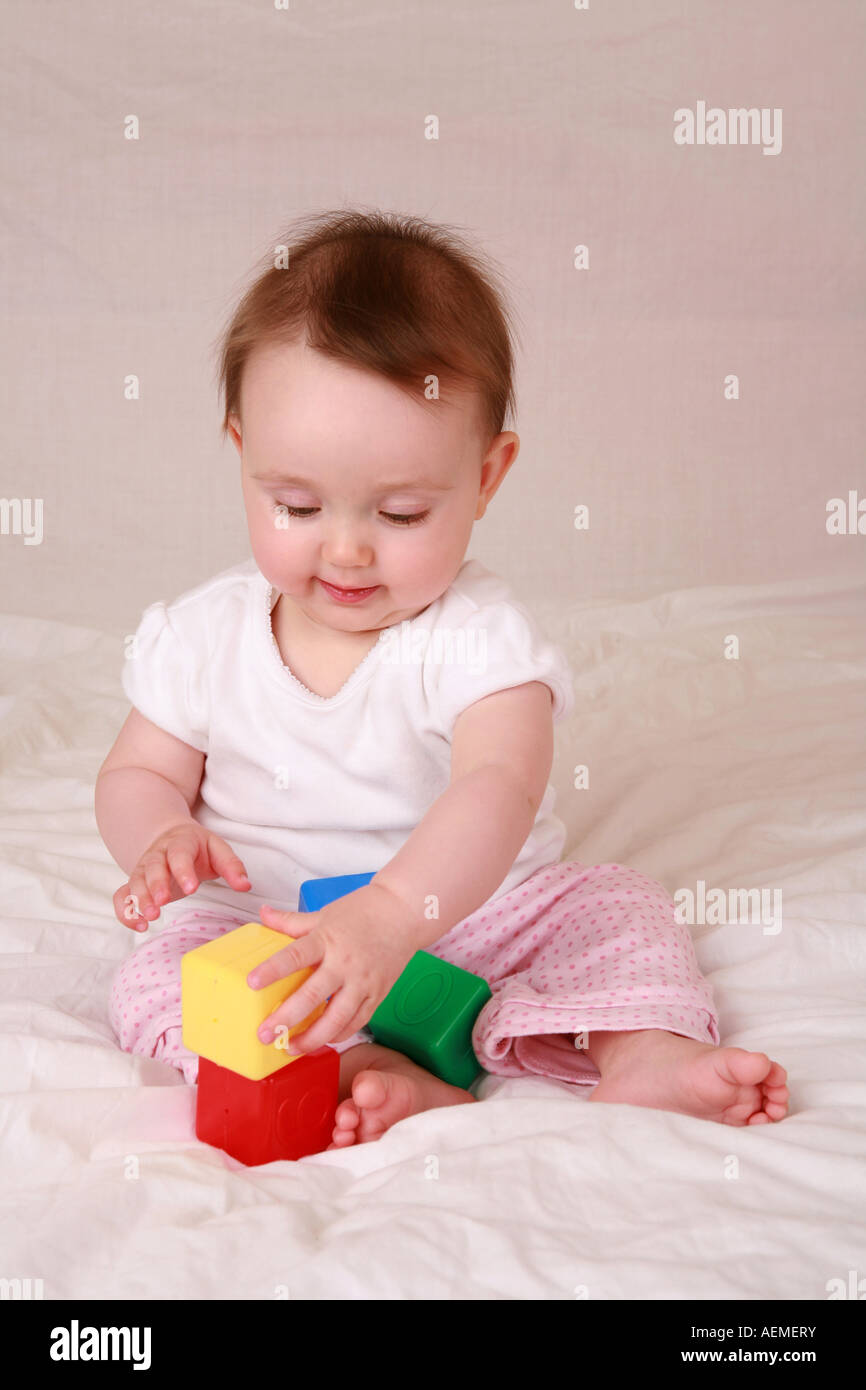 Cute angelic newborn baby infant in first year sitting upright playing ...